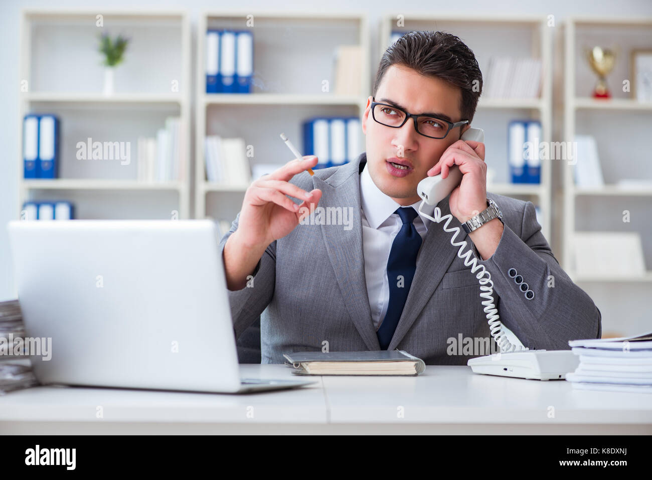 Businessman smoking in office at work Stock Photo - Alamy