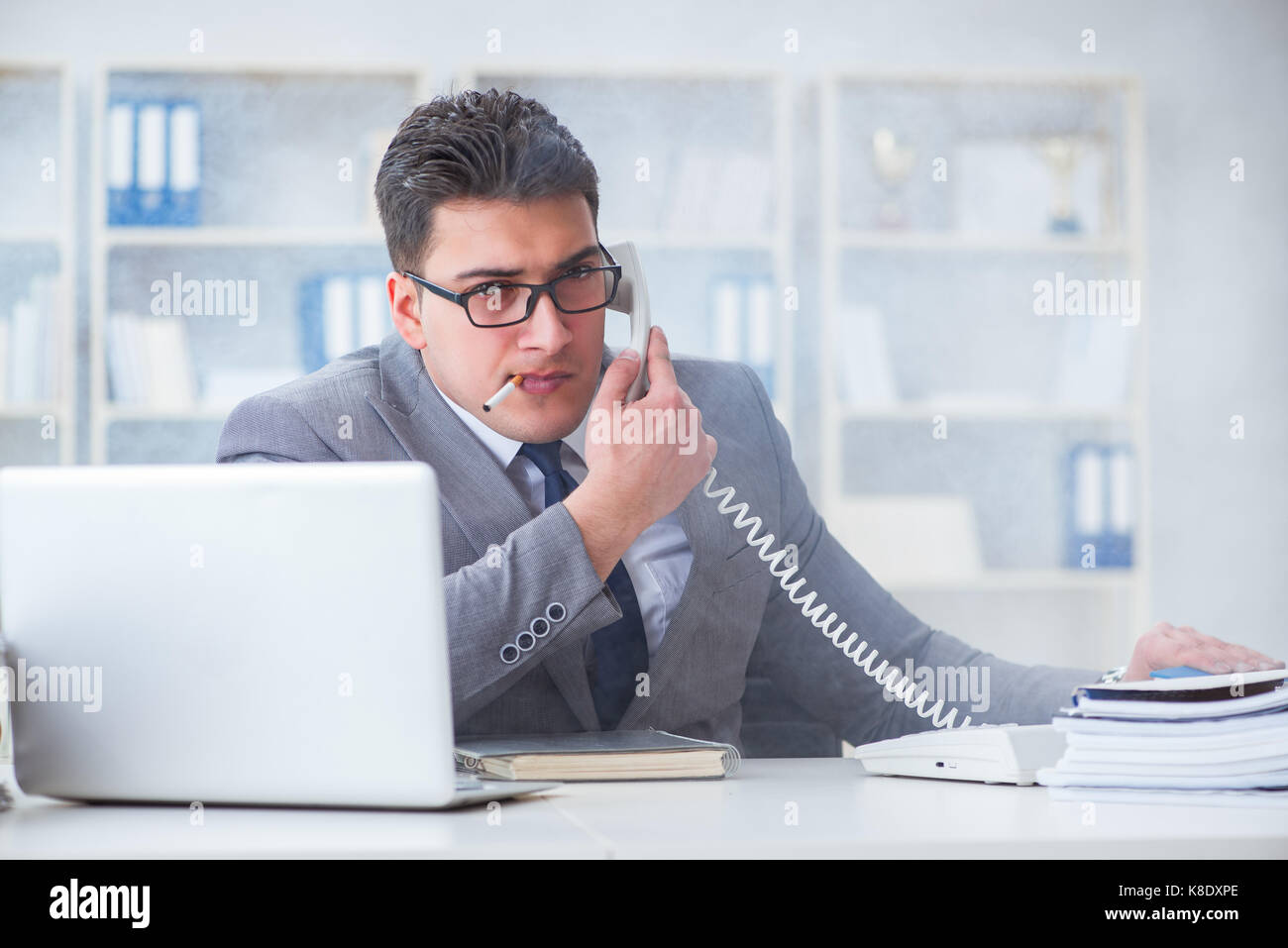 Businessman smoking in office at work Stock Photo - Alamy