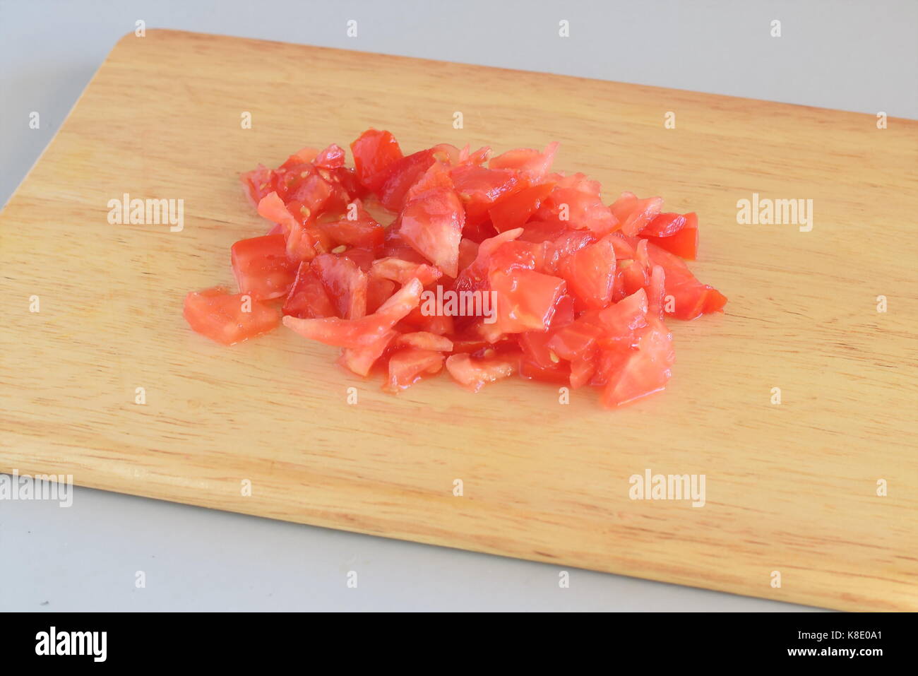 Step by step cooking. Fresh chopped tomato on a wooden cutting board on ...
