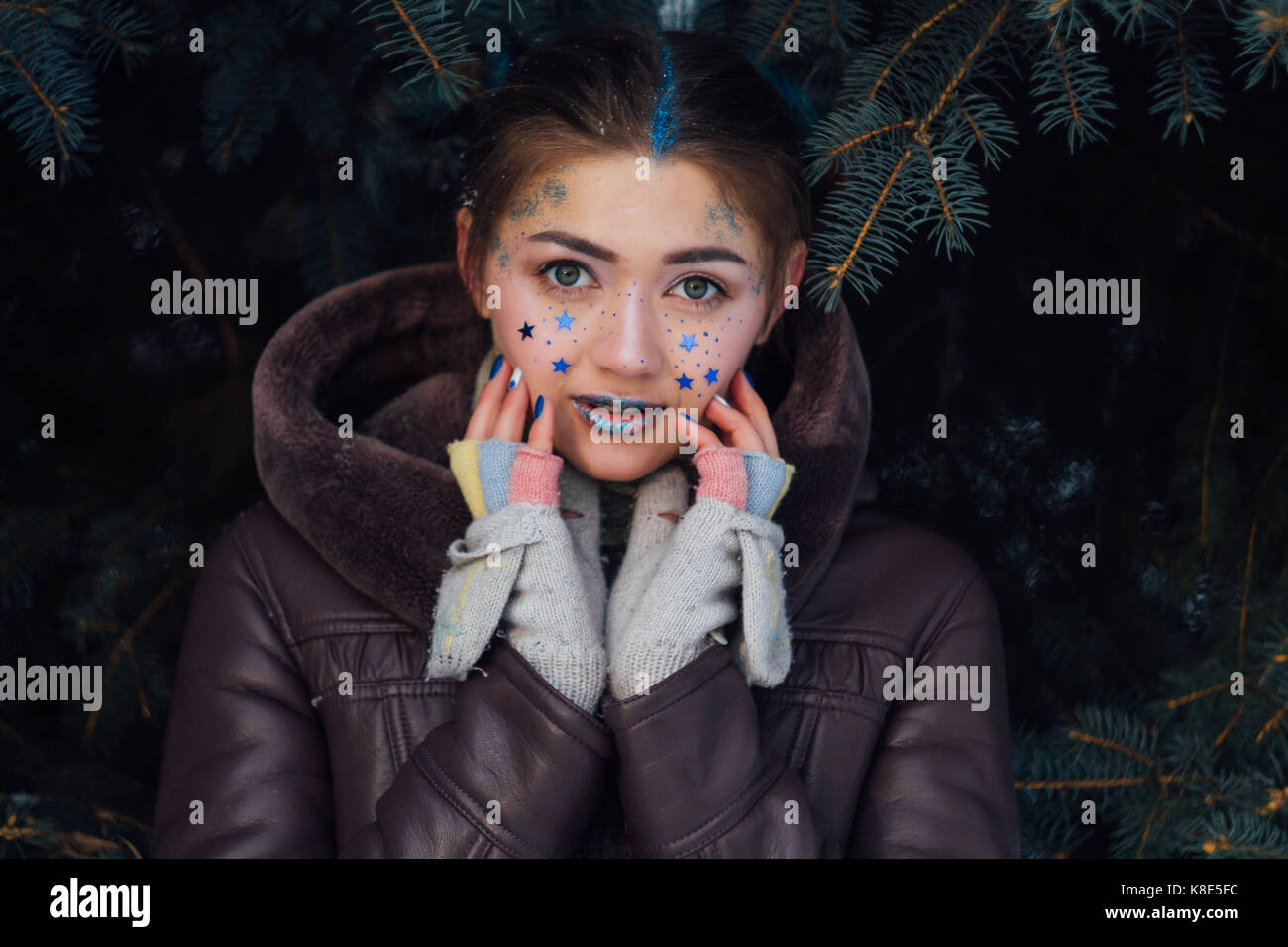 Winter portrait of a girl with bright make up and blue stars on face ...