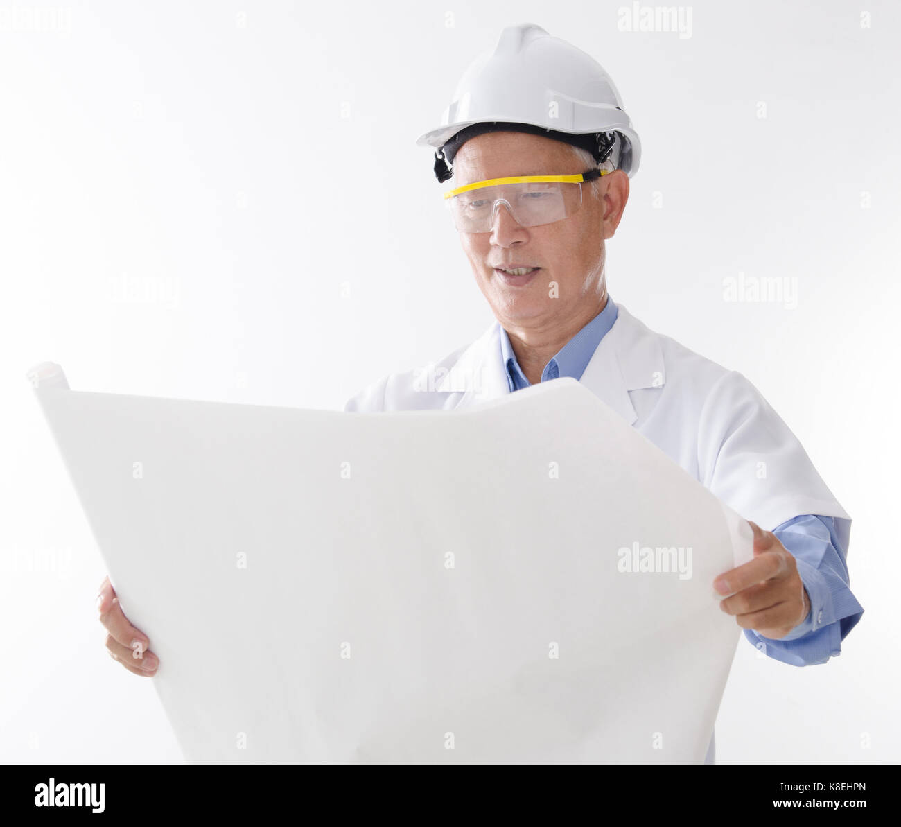 Portrait of Asian contractor with hard hat reading on blueprint ...