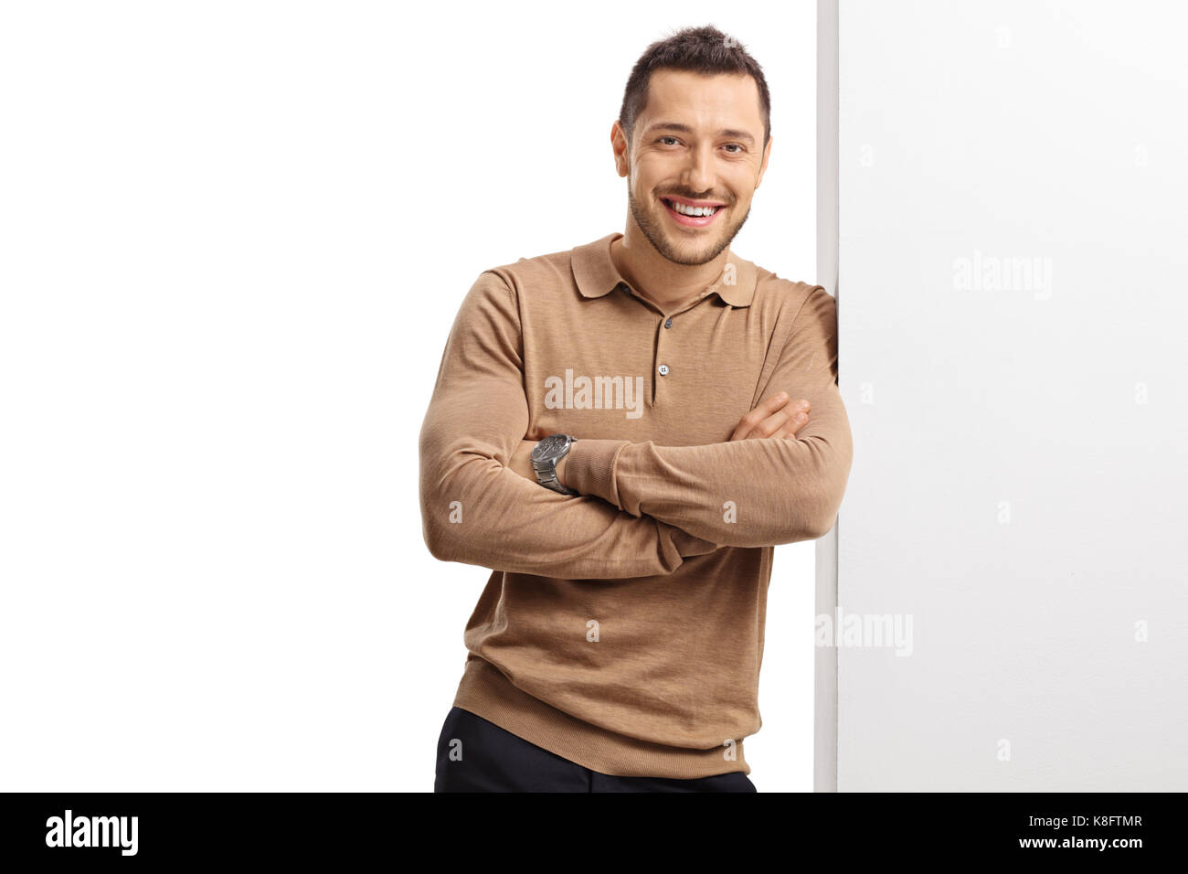 Young man leaning against a wall and smiling isolated on white ...