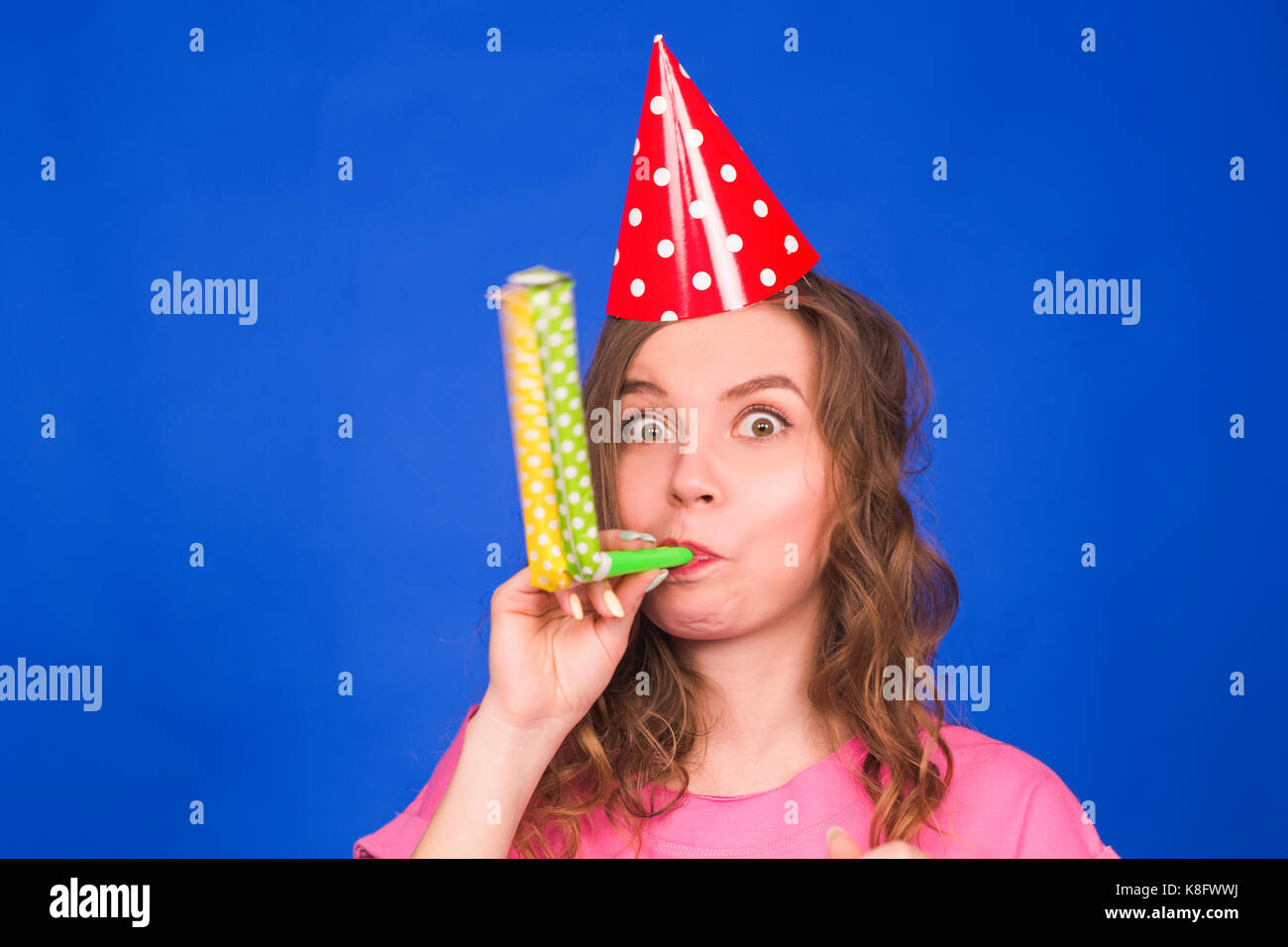 Young woman blowing two party whistles against blue background Stock ...