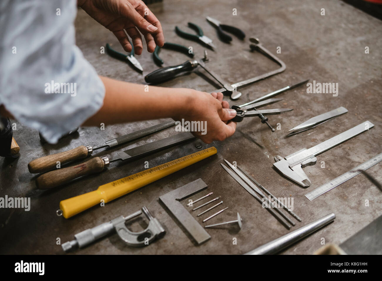 Hands of female jeweller laying out hand tools at workbench in ...