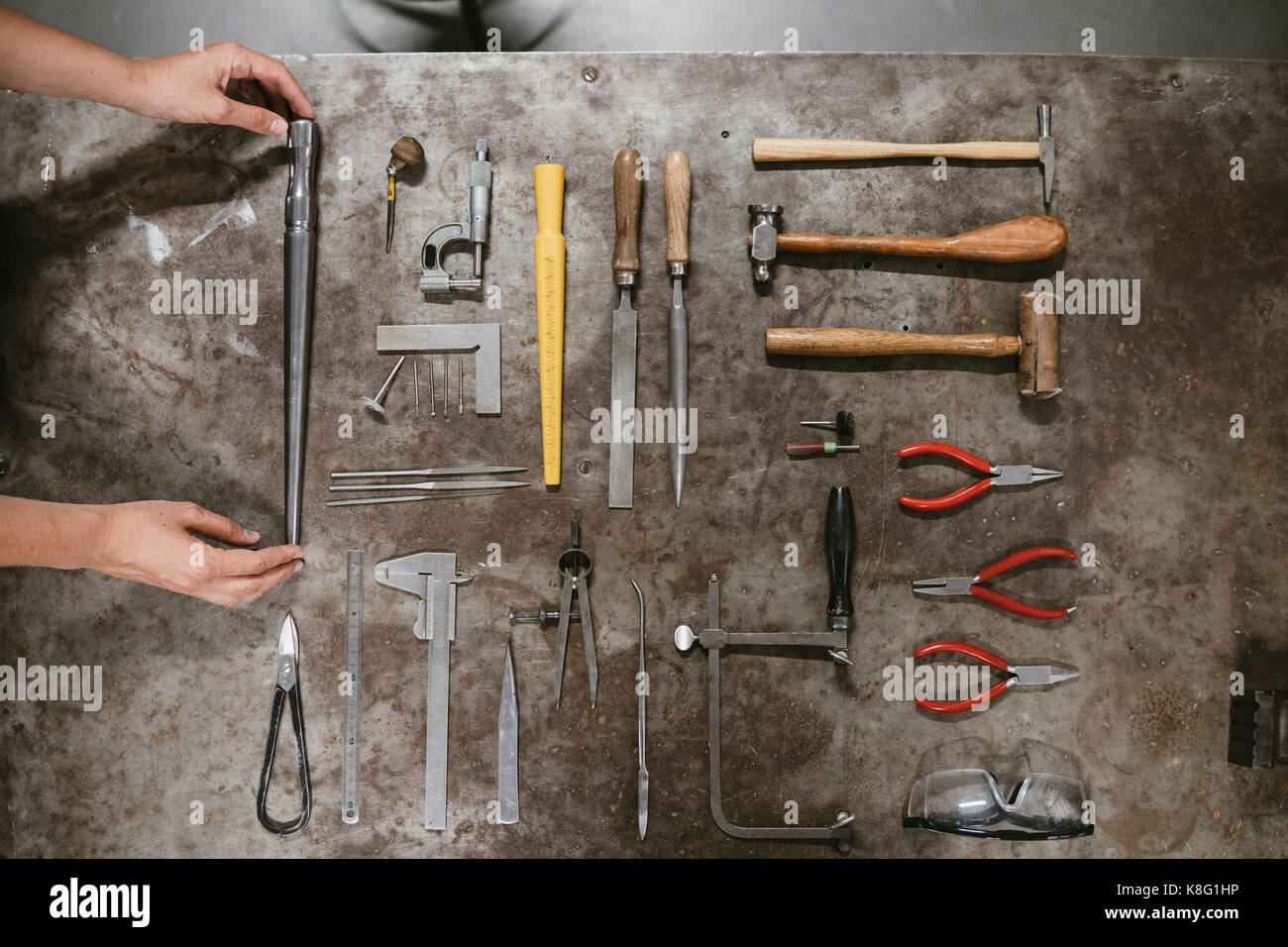 Overhead view of female jeweller's hands laying out hand tools at ...