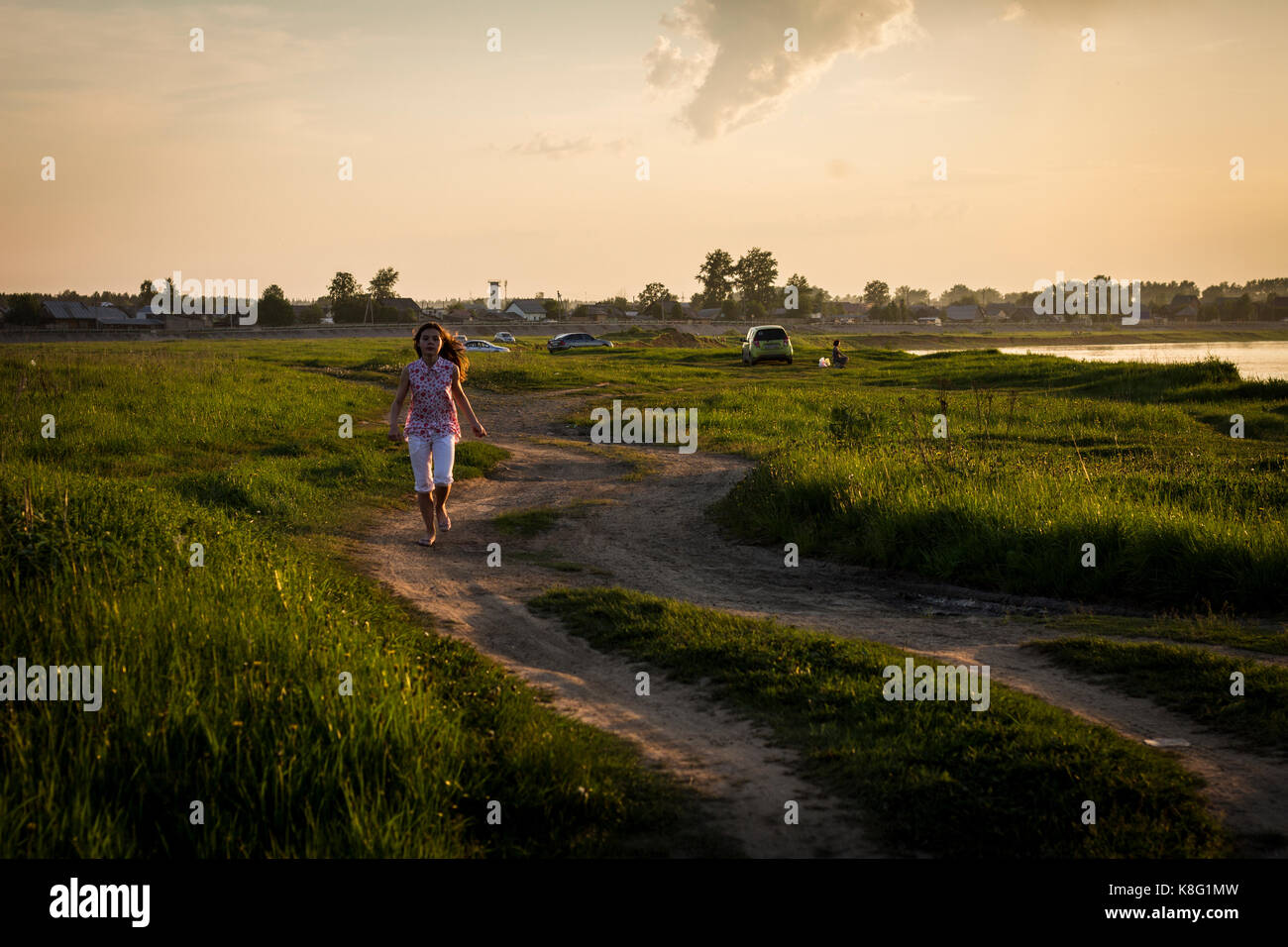 Lone teenage girl running along rural dirt track at sunset Stock Photo ...