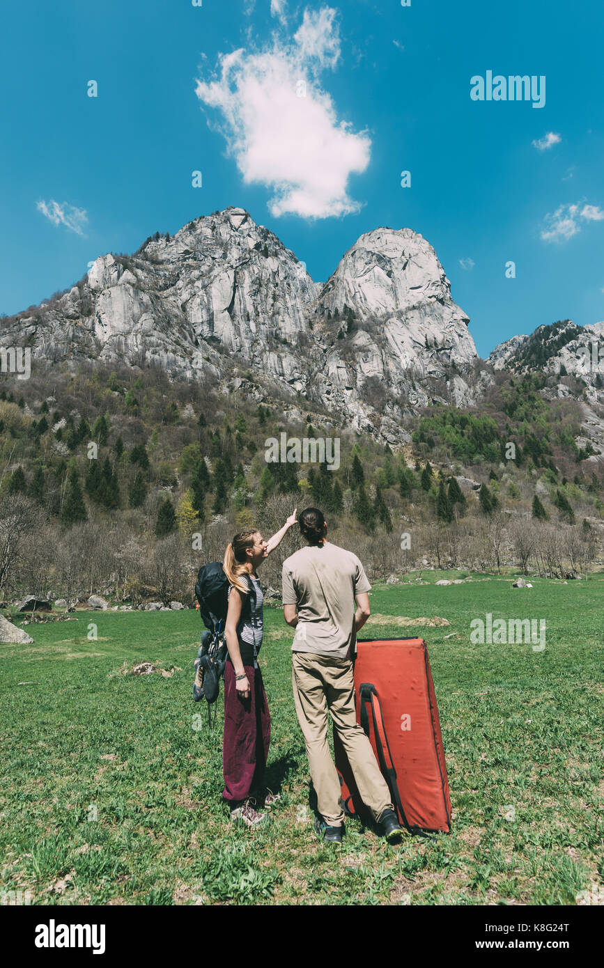 Young male and female boulderers looking up at mountain, Lombardy ...