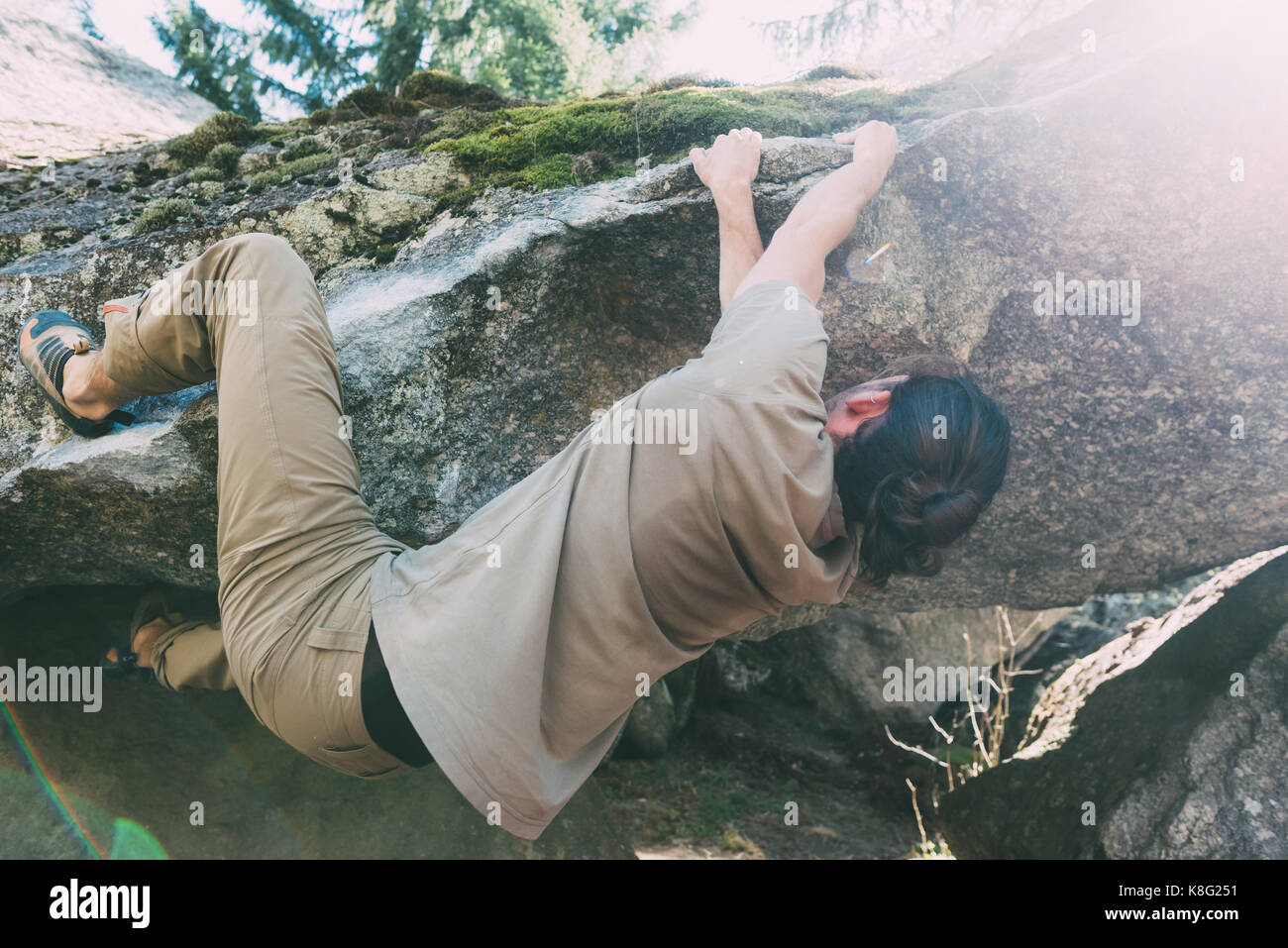 Young male boulderer climbing edge of boulder, Lombardy, Italy Stock ...