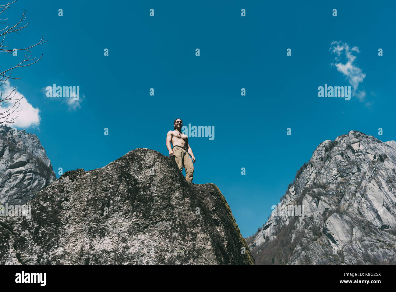 Low angle view of bare chested young male boulderer looking down ...