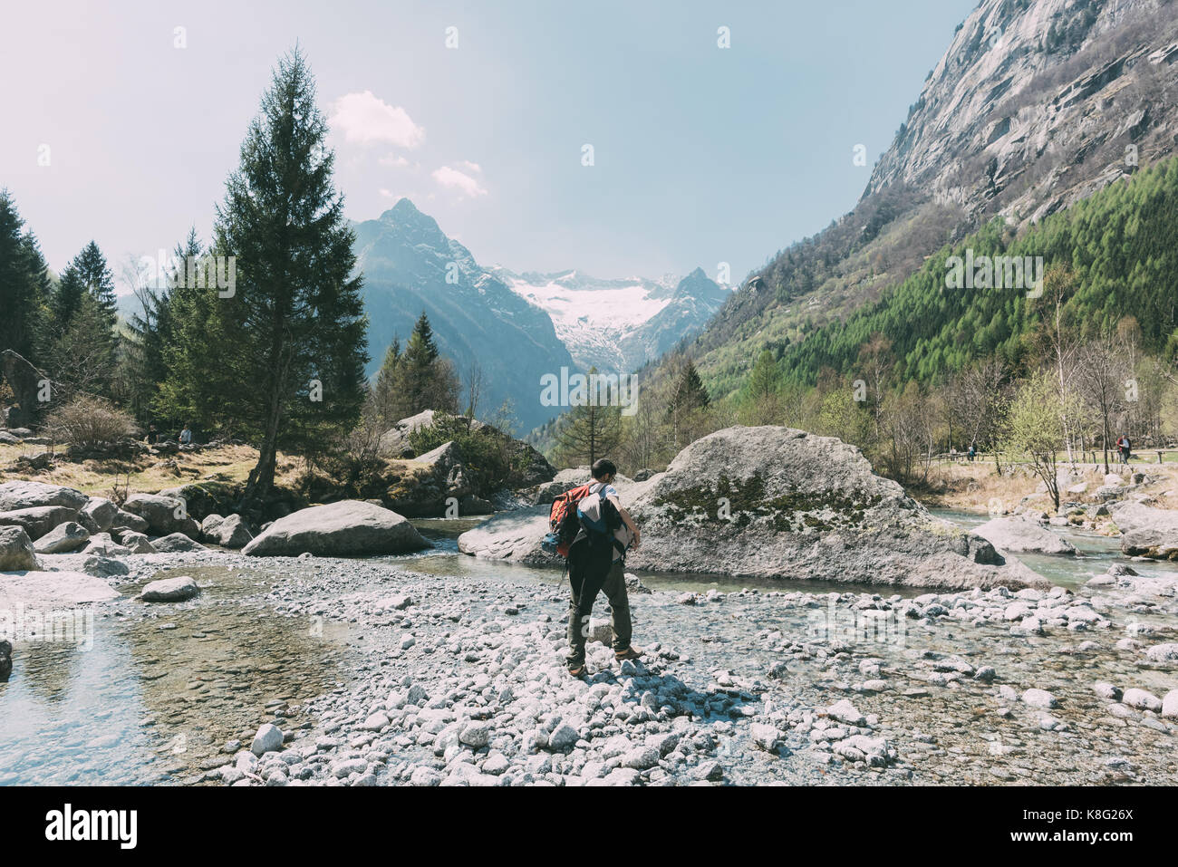 Rear view of male boulderer standing by valley river, Lombardy, Italy ...