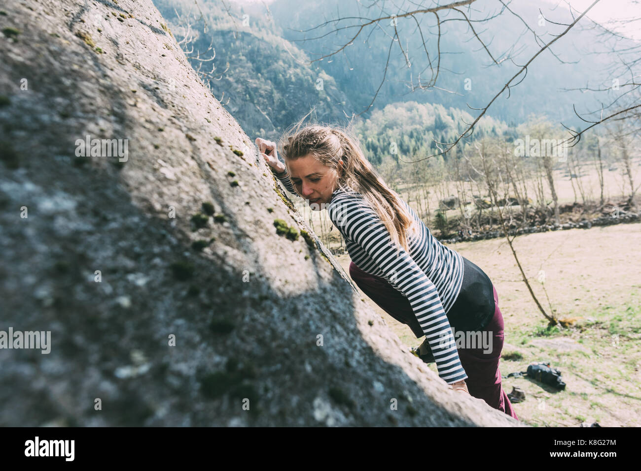 Young female boulderer climbing up boulder, Lombardy, Italy Stock Photo ...