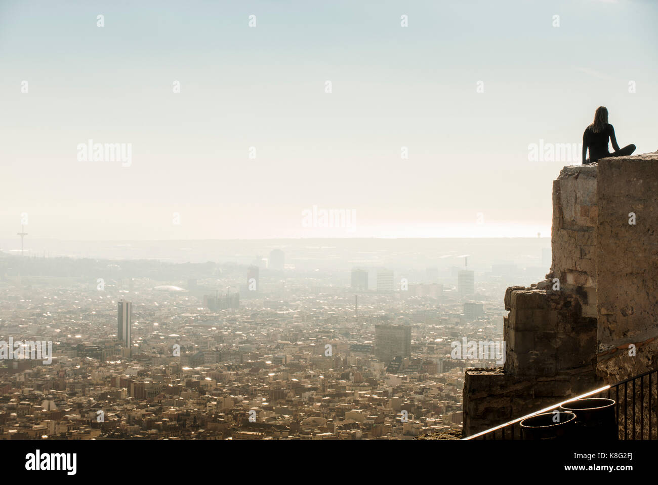 Backlit female tourist looking out from top of wall at Barcelona ...