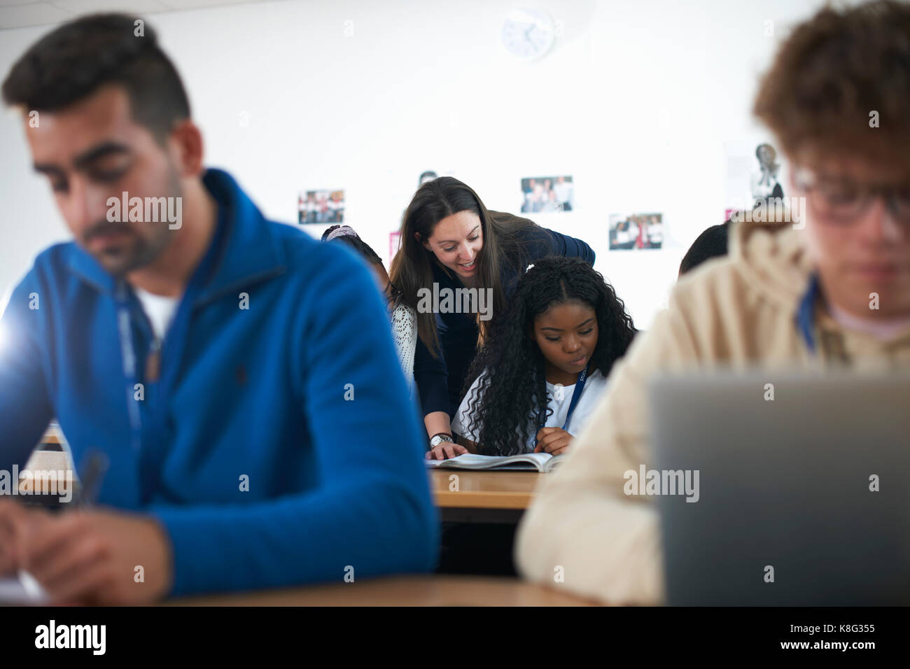 Teacher in classroom helping students study Stock Photo - Alamy