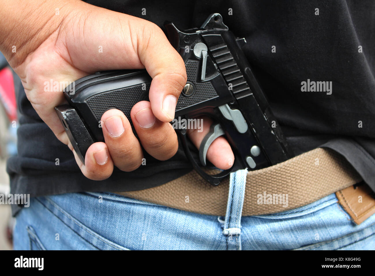 gangster concealing his gun behind his back Stock Photo - Alamy