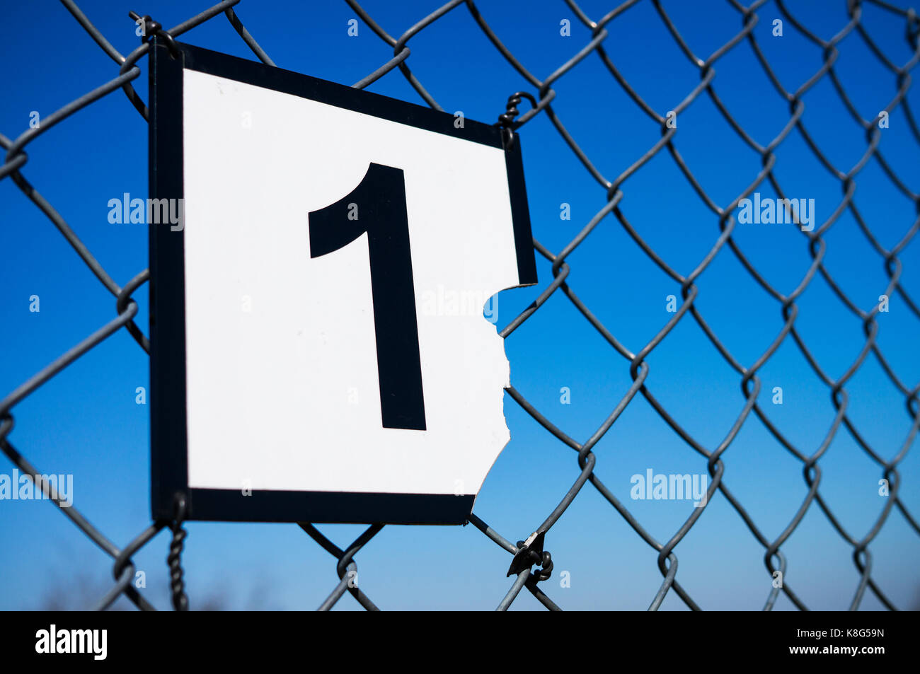 Broken plaque with number one attached to metal fence Stock Photo - Alamy