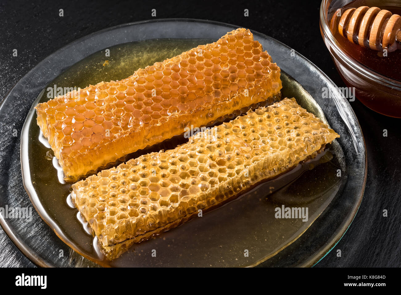 Honey and honeycomb on black dish Stock Photo - Alamy