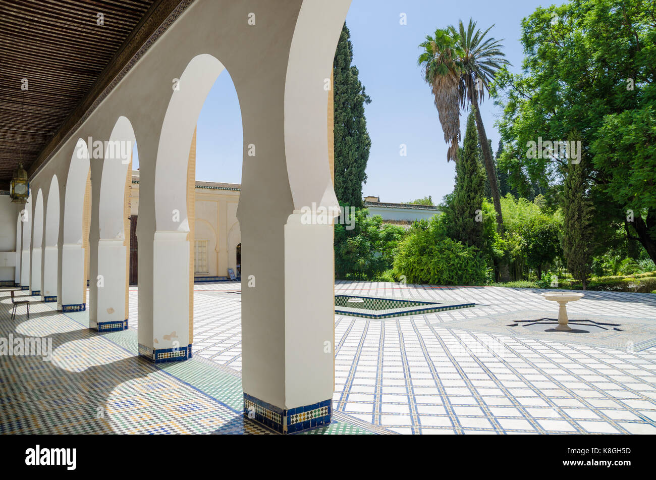 Beautiful white arches of arabic building with lush green garden in ...