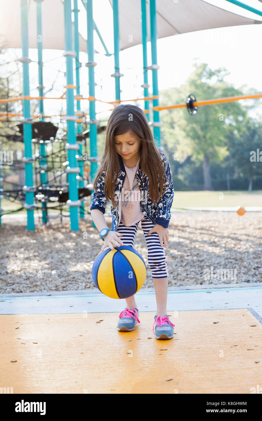 Girl bouncing basketball in playground Stock Photo - Alamy