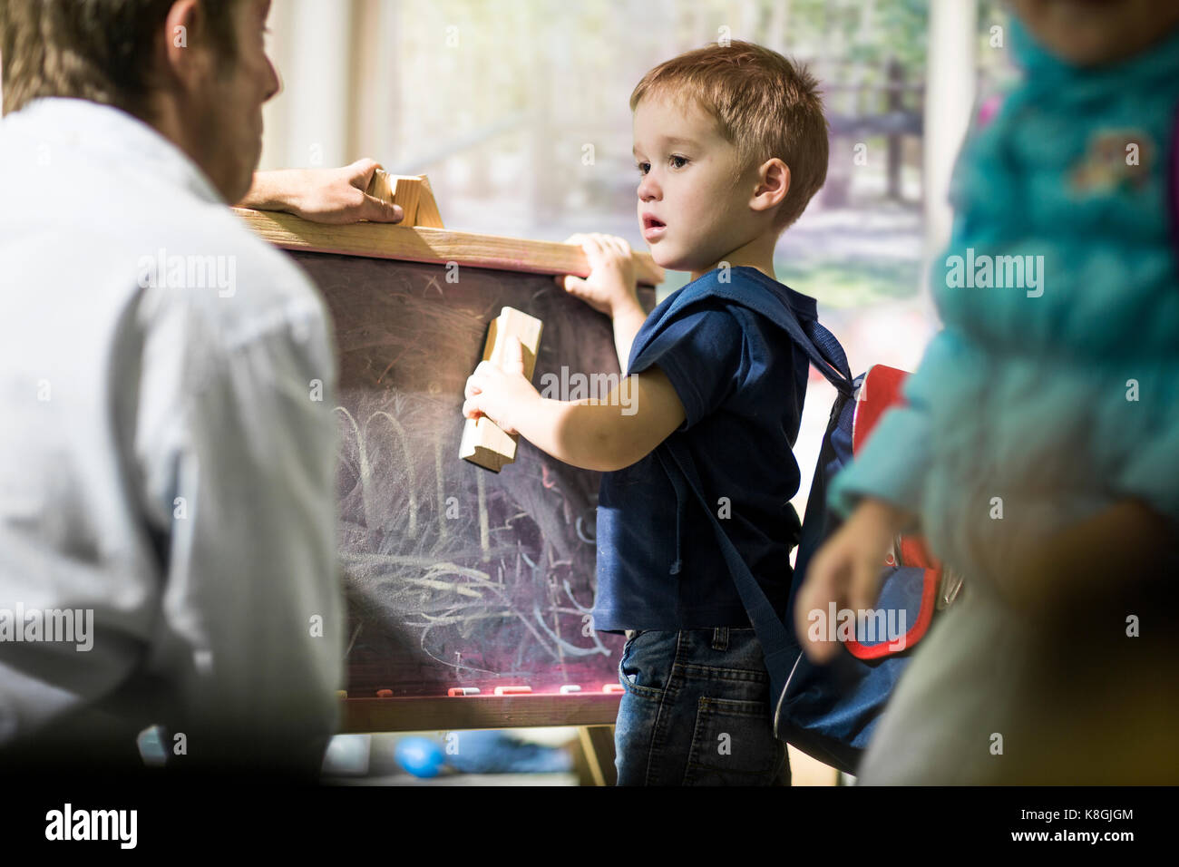 Boy cleaning blackboard with duster Stock Photo - Alamy