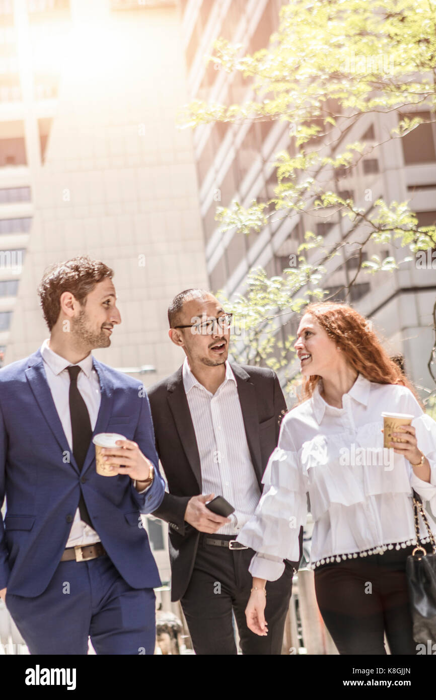 Businessmen and woman strolling along city sidewalk, New York, USA ...