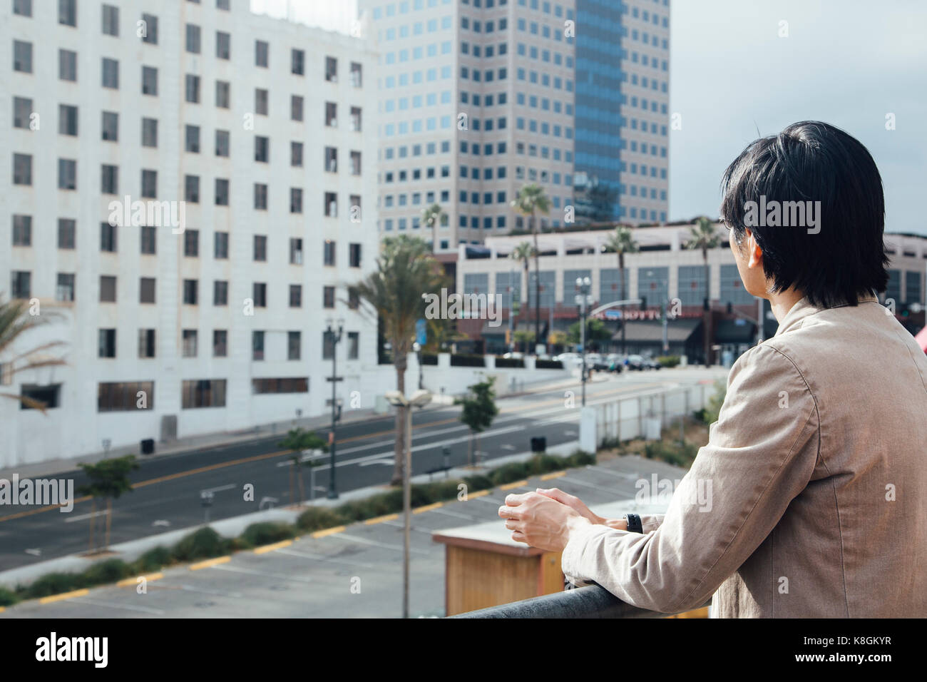 Young man leaning on railings, looking at office building Stock Photo ...