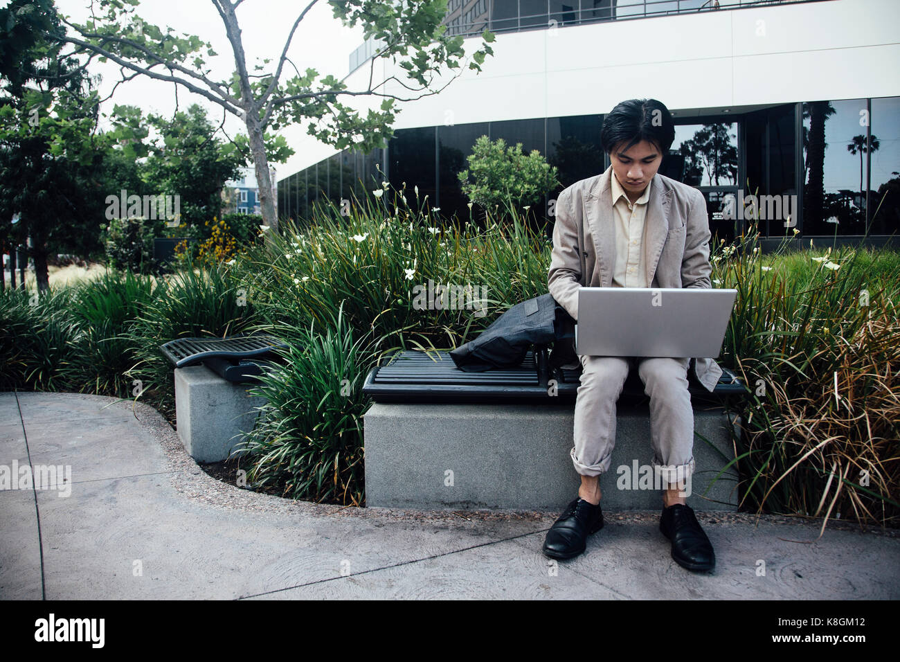 Young man sitting outdoors, using laptop Stock Photo - Alamy