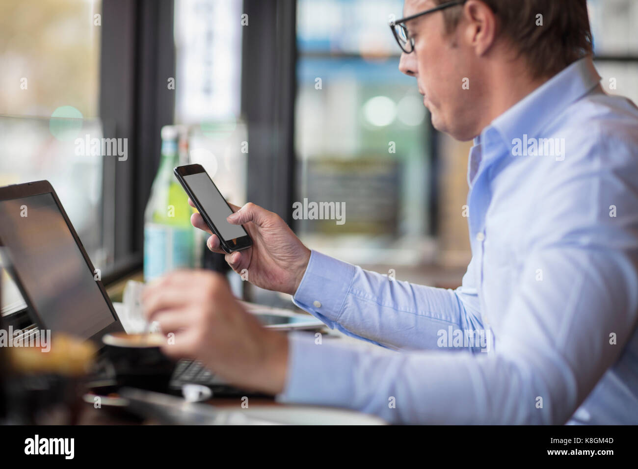 Man in coffee shop using smartphone Stock Photo - Alamy