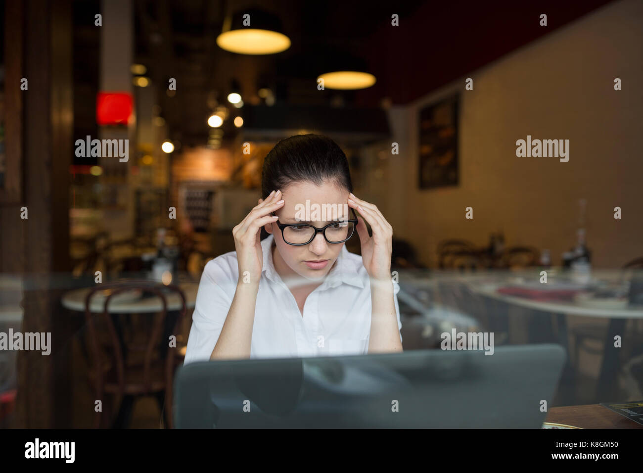 Woman in coffee shop using laptop looking stressed Stock Photo - Alamy
