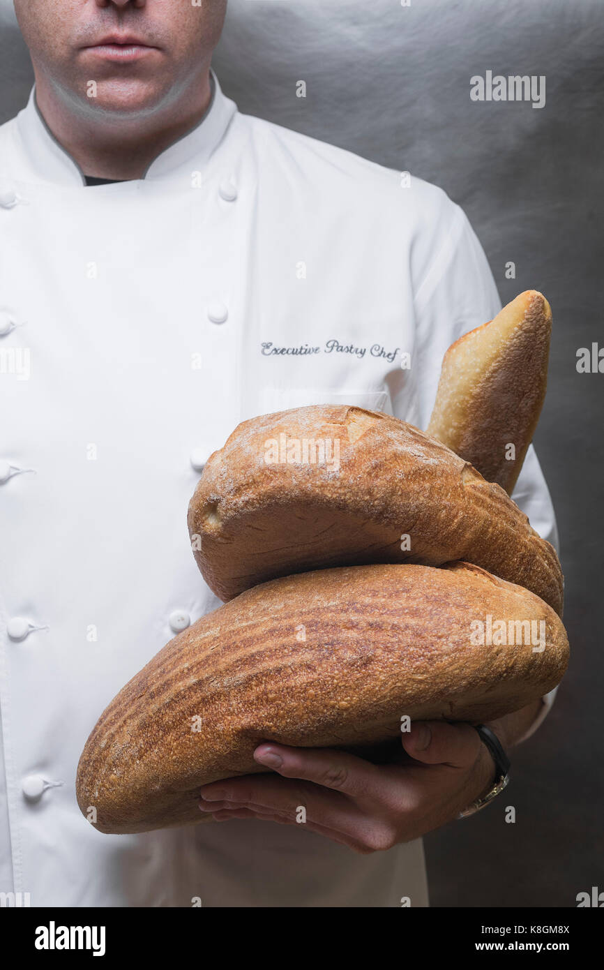 Cropped portrait of pastry chef holding loaves in kitchen Stock Photo ...