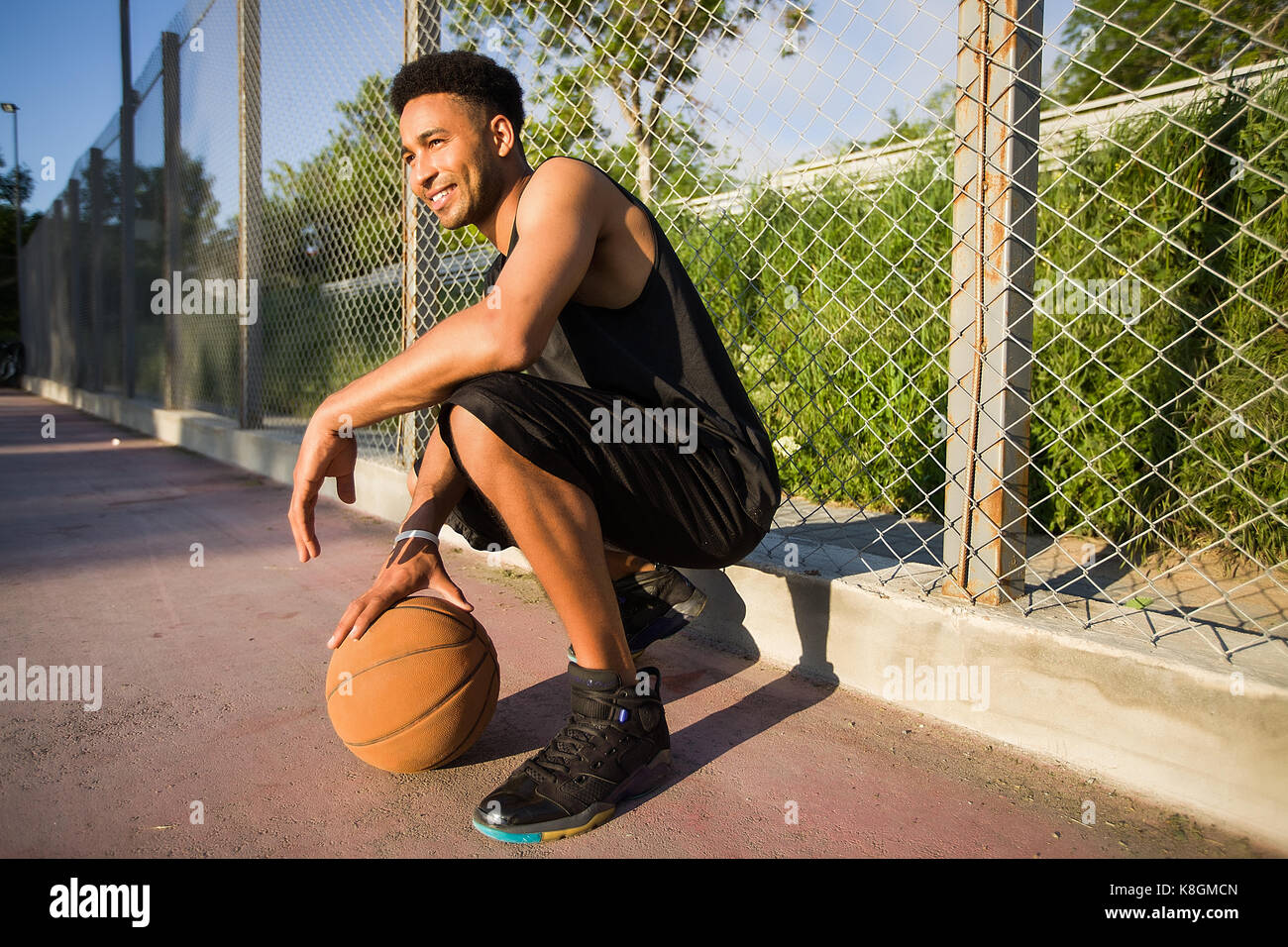 Young man on basketball court, crouching with ball Stock Photo - Alamy