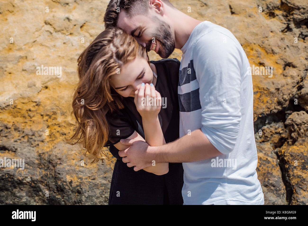 Couple laughing beside rock Stock Photo - Alamy