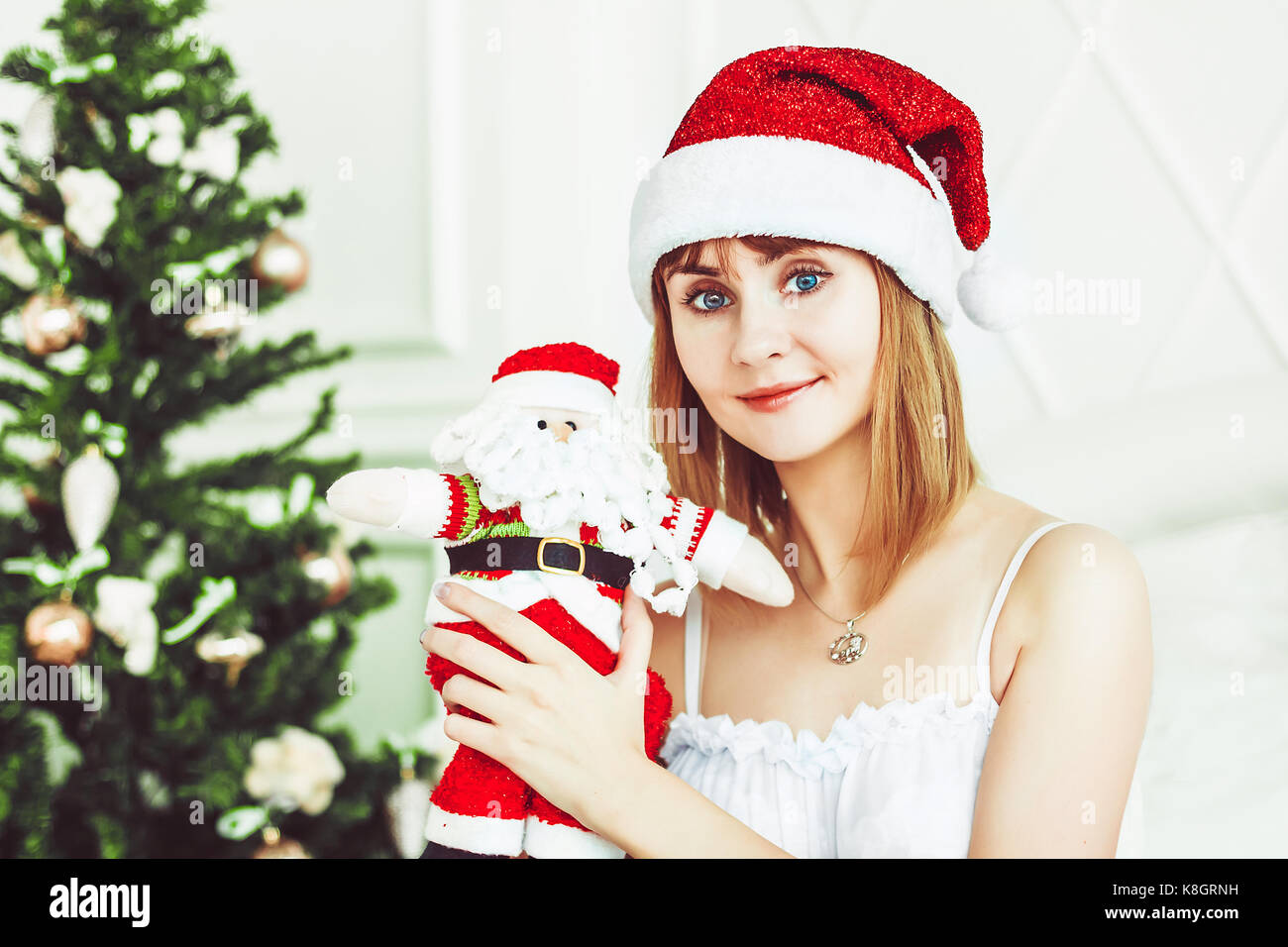 Pretty girl holding Santa Clause plush toy. Smiling woman holding small ...