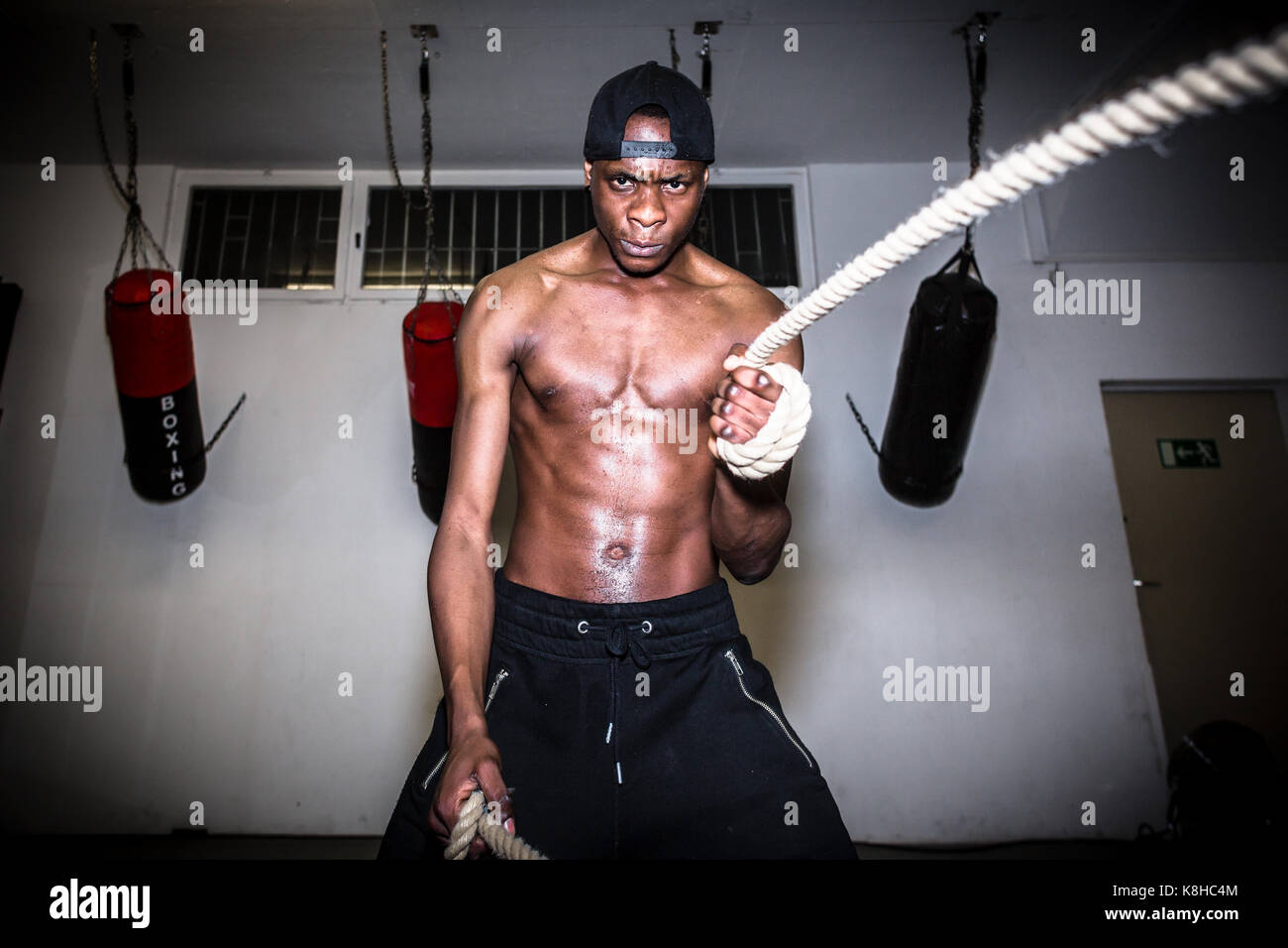 Portrait of young determined man waving battle ropes during high Stock ...