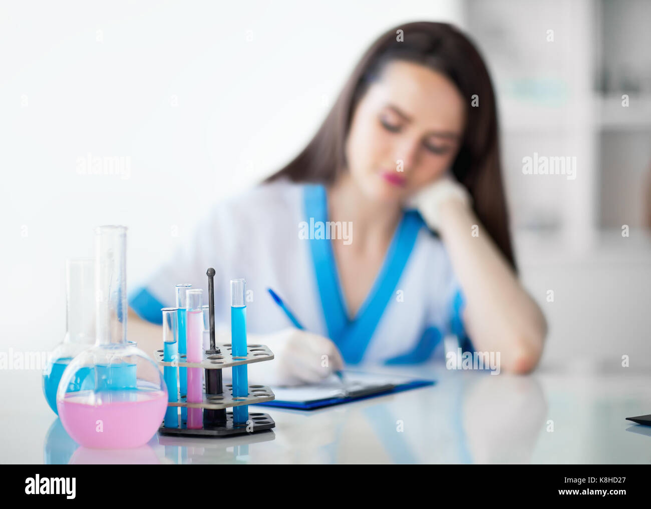 Portrait of beautiful female scientist writing notes in laboratory ...