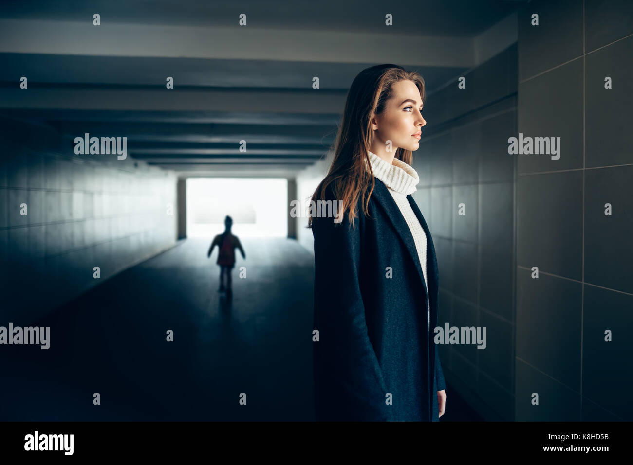 Beautiful lonely woman in a subway tunnel with frighten silhouette on ...
