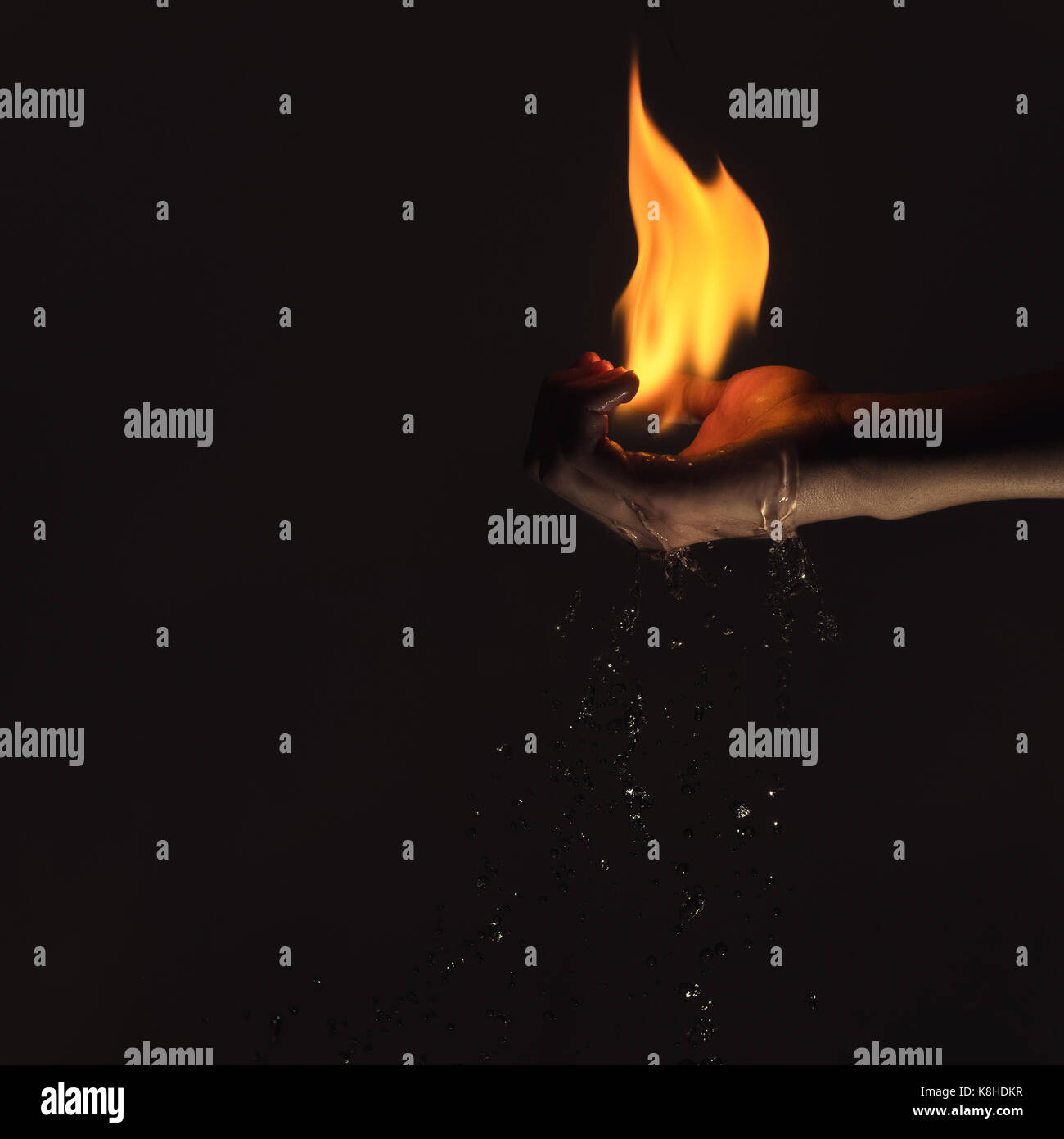 A hand is holding fire while water is pouring down itself Stock Photo ...
