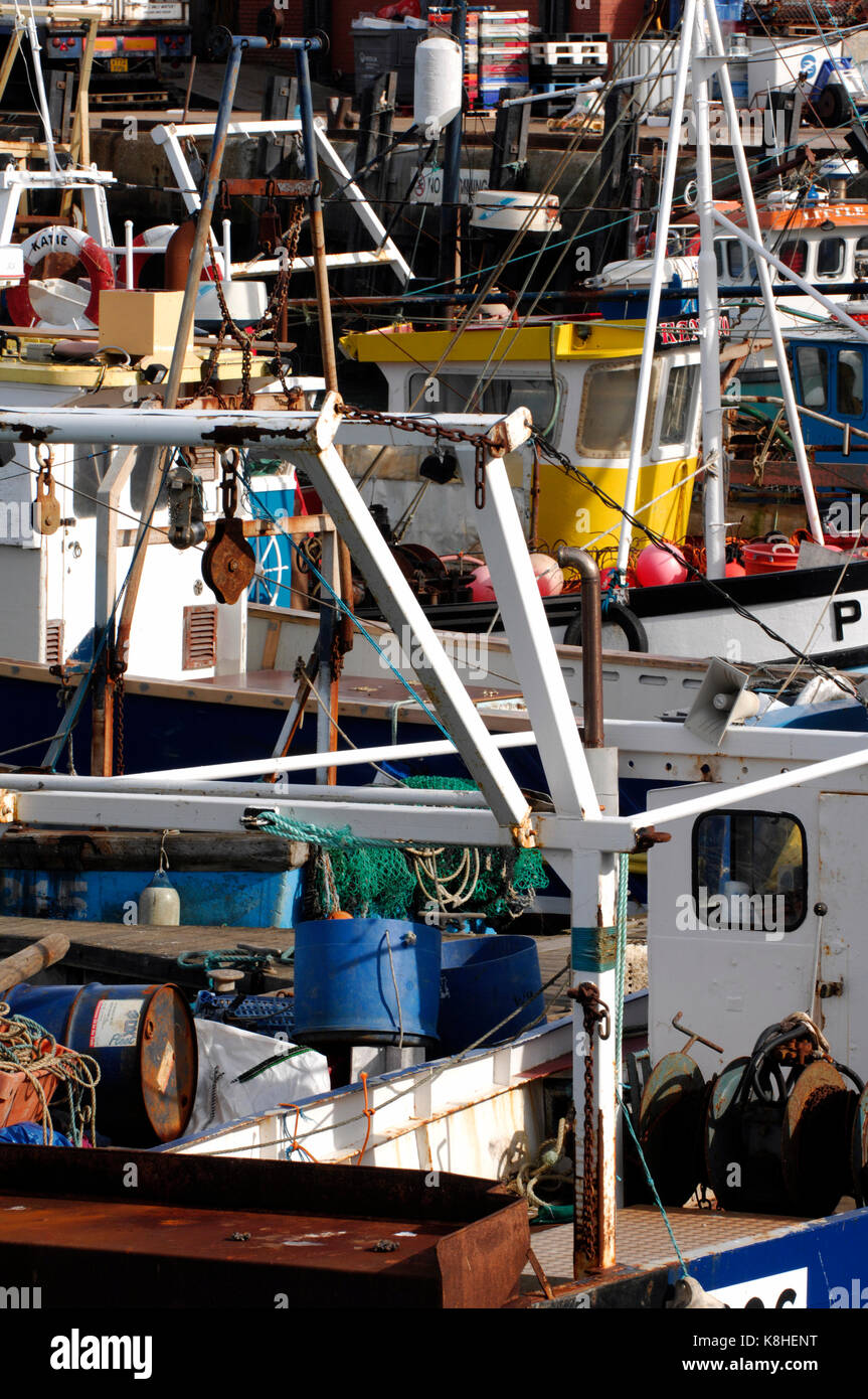 fishing boats and trawlers together in a packed and busy fisherman dock ...