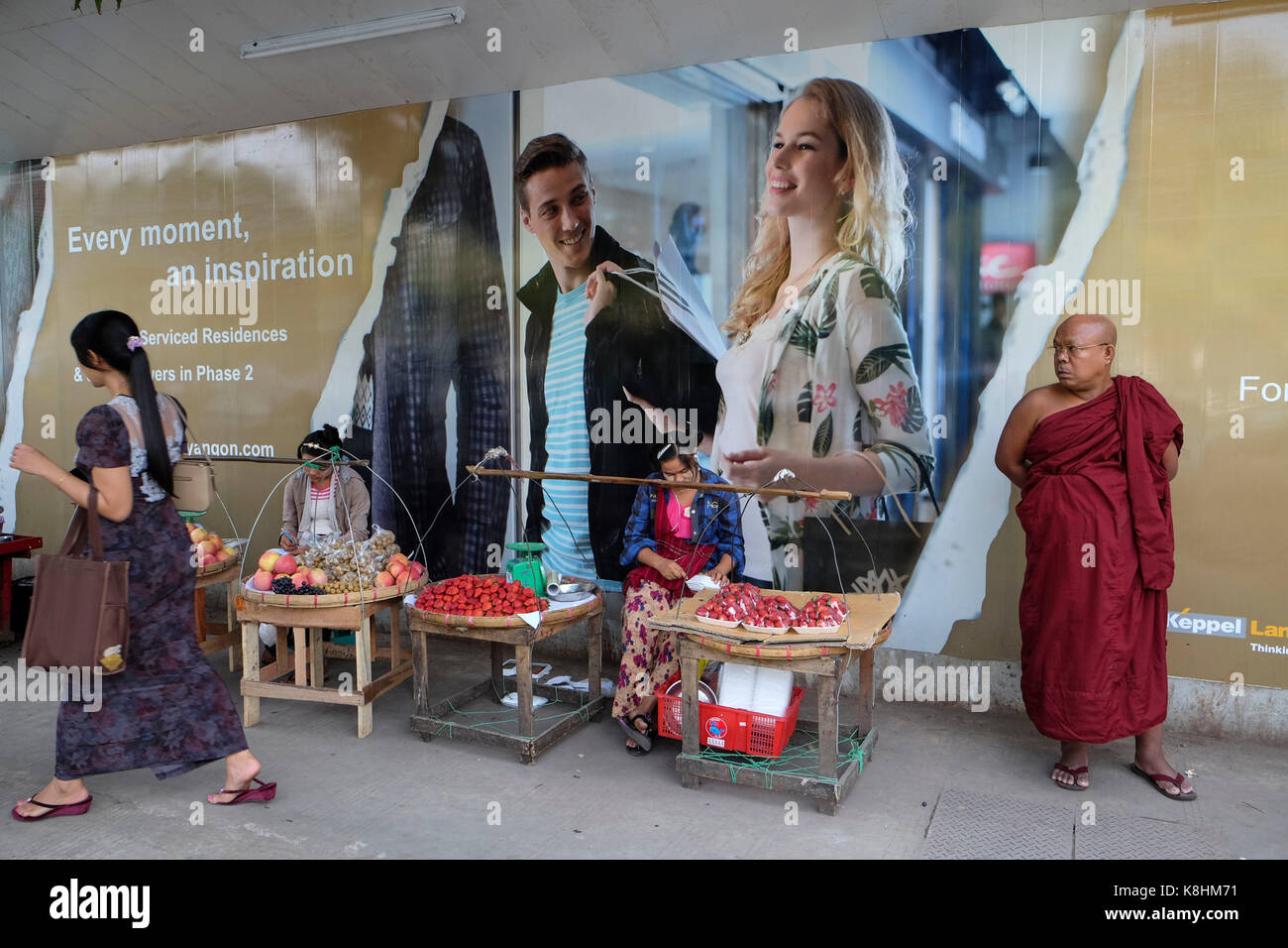 Burma, Myanmar: Buddhist monk, fruit peddlers and poster in a street of ...
