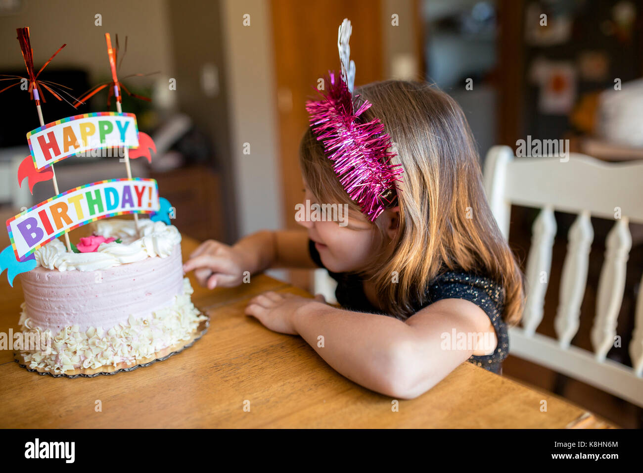 High angle view of girl touching birthday cake while sitting on chair ...
