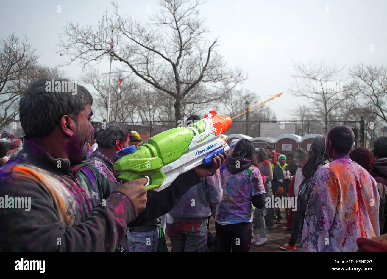 A boy soaks powder-covered revelers with his water pistol at the ...