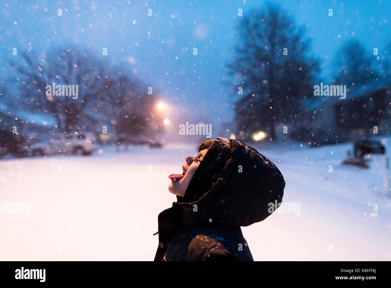 Playful boy catching snowflakes on tongue Stock Photo - Alamy