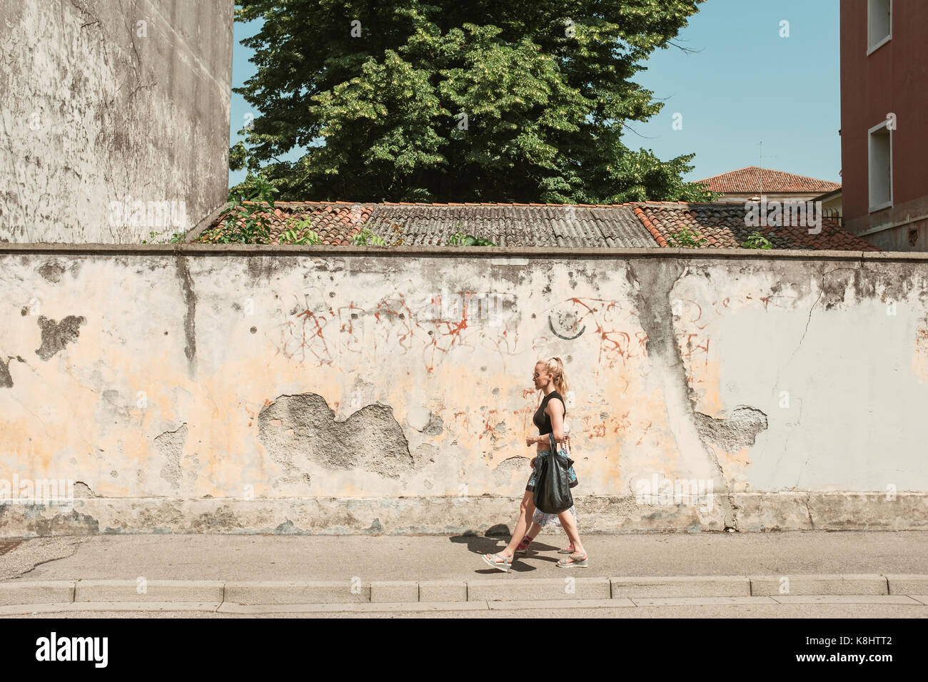 Side view of mother and daughter walking on sidewalk during sunny day ...