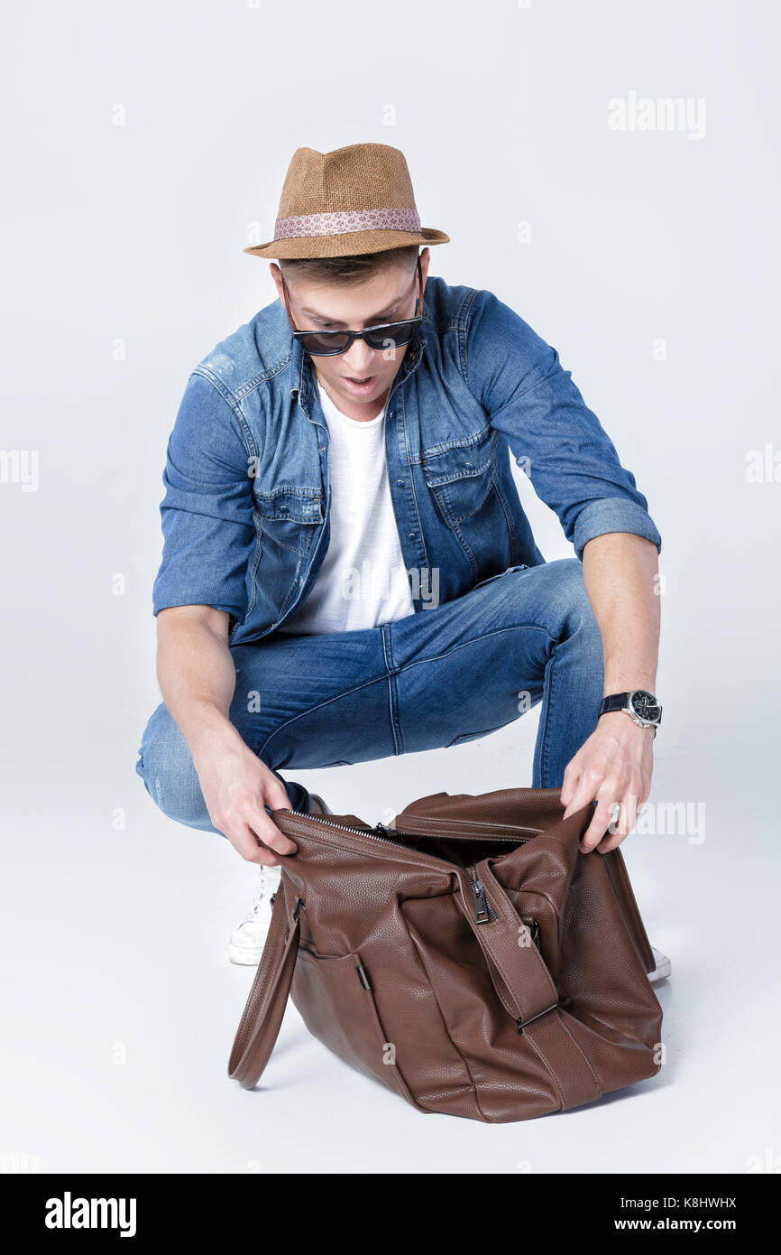 surprised man in a hat looks in an empty leather bag Stock Photo - Alamy