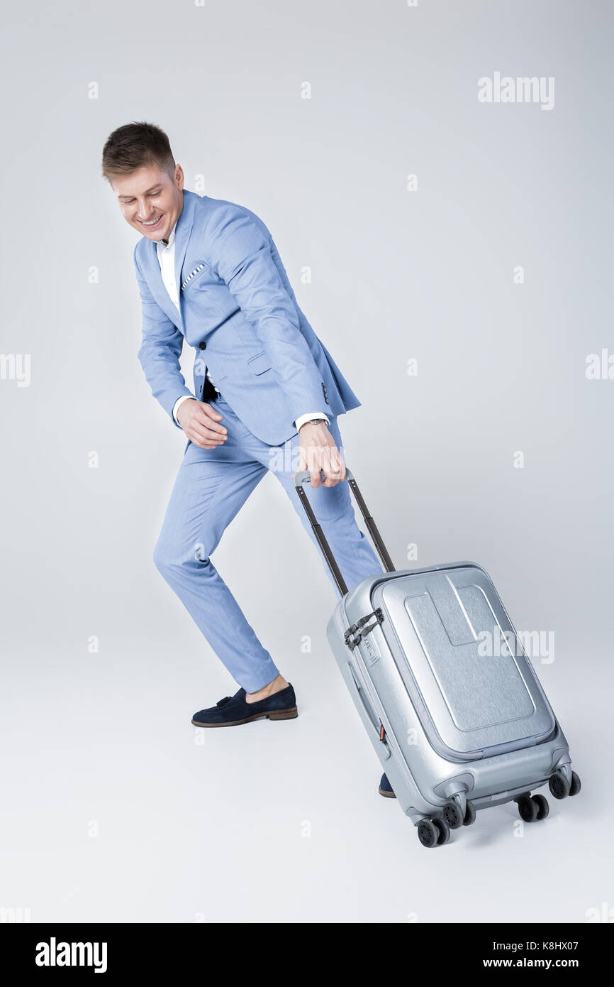 young man in blue suit with suitcase Stock Photo - Alamy