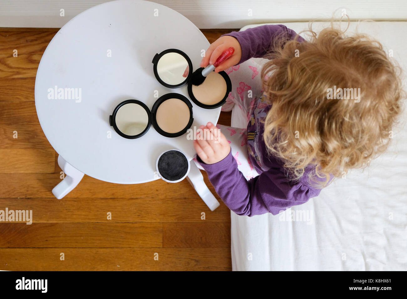 Overhead view of girl holding make-up brush over concealers at table ...