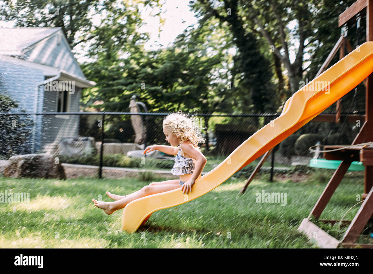 Playful girl playing on slide at playground Stock Photo - Alamy