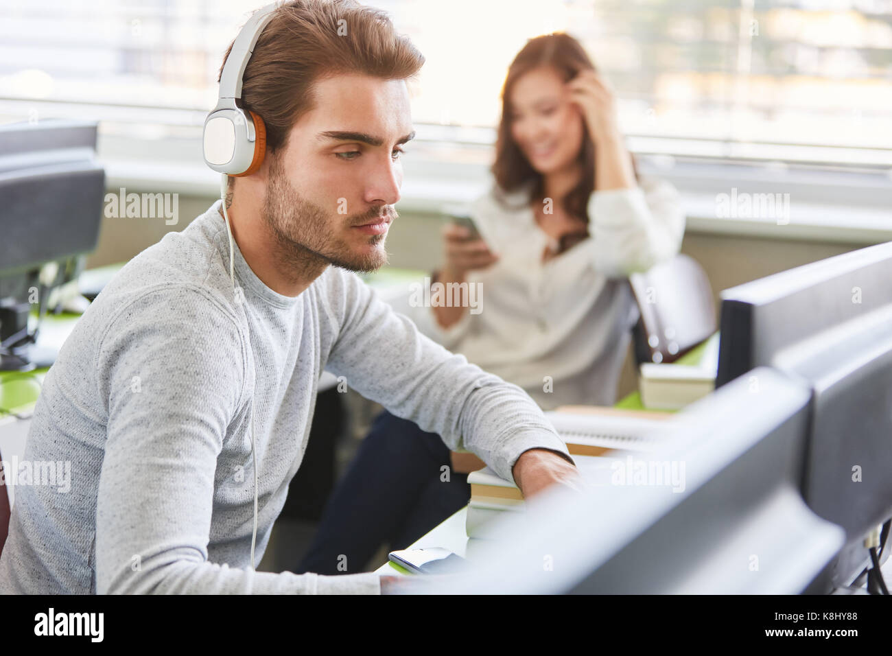 Student as programmer with computer wearing headphones in university ...