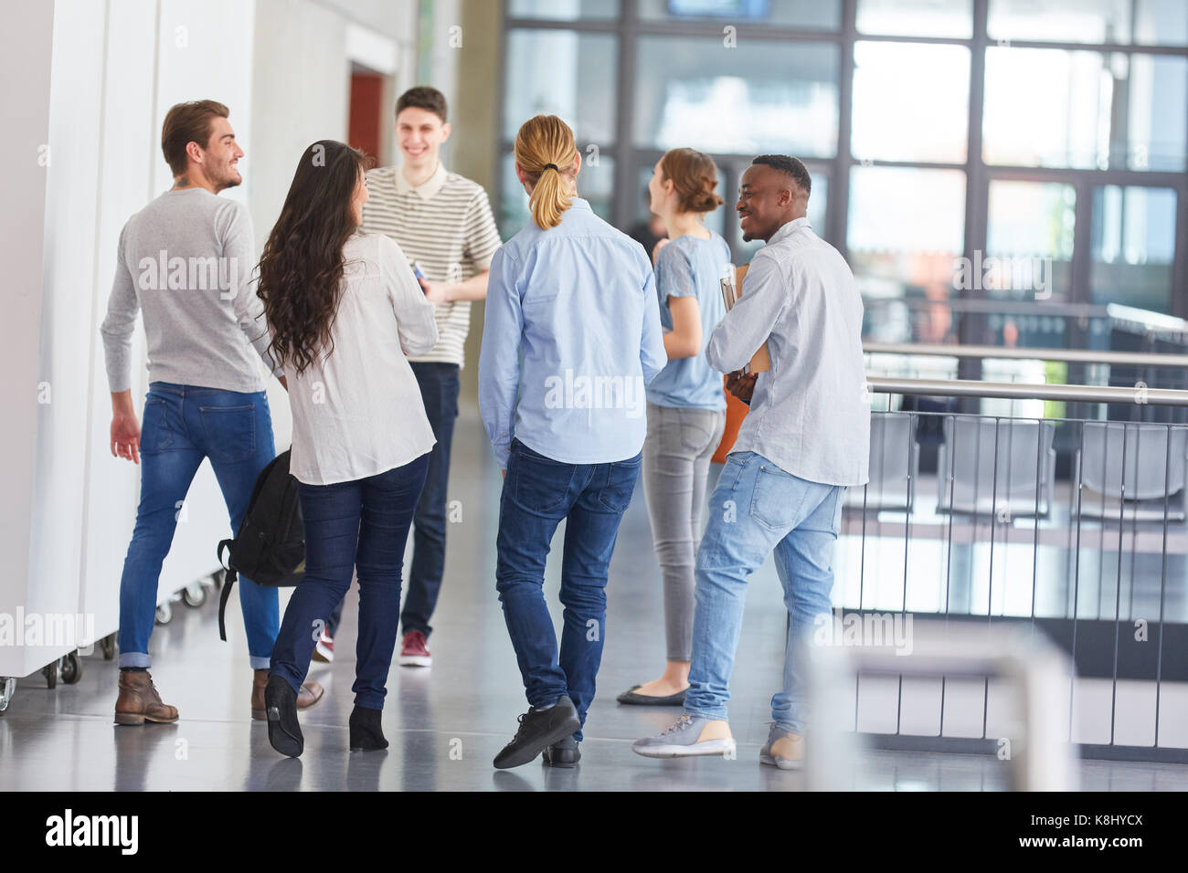Students make small talk in university hallway as group Stock Photo - Alamy