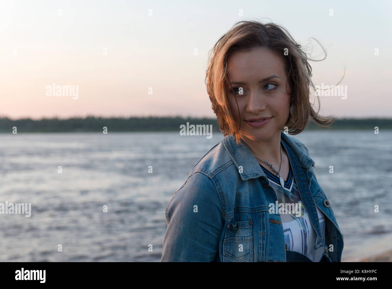 beautiful girl looks away on the river and sunset background Stock ...