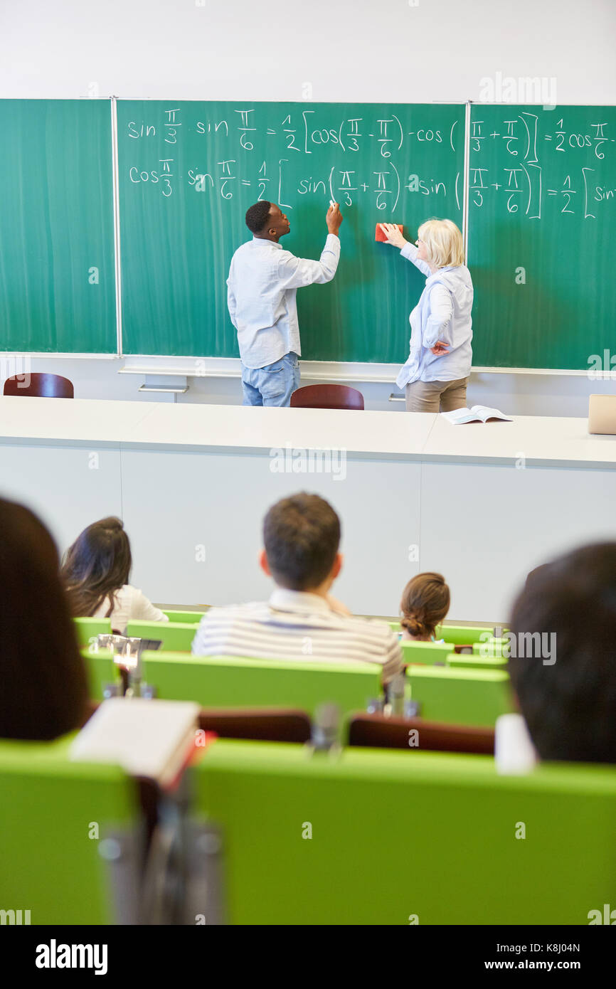 Student or pupil calculating math formula on university hall chalkboard ...